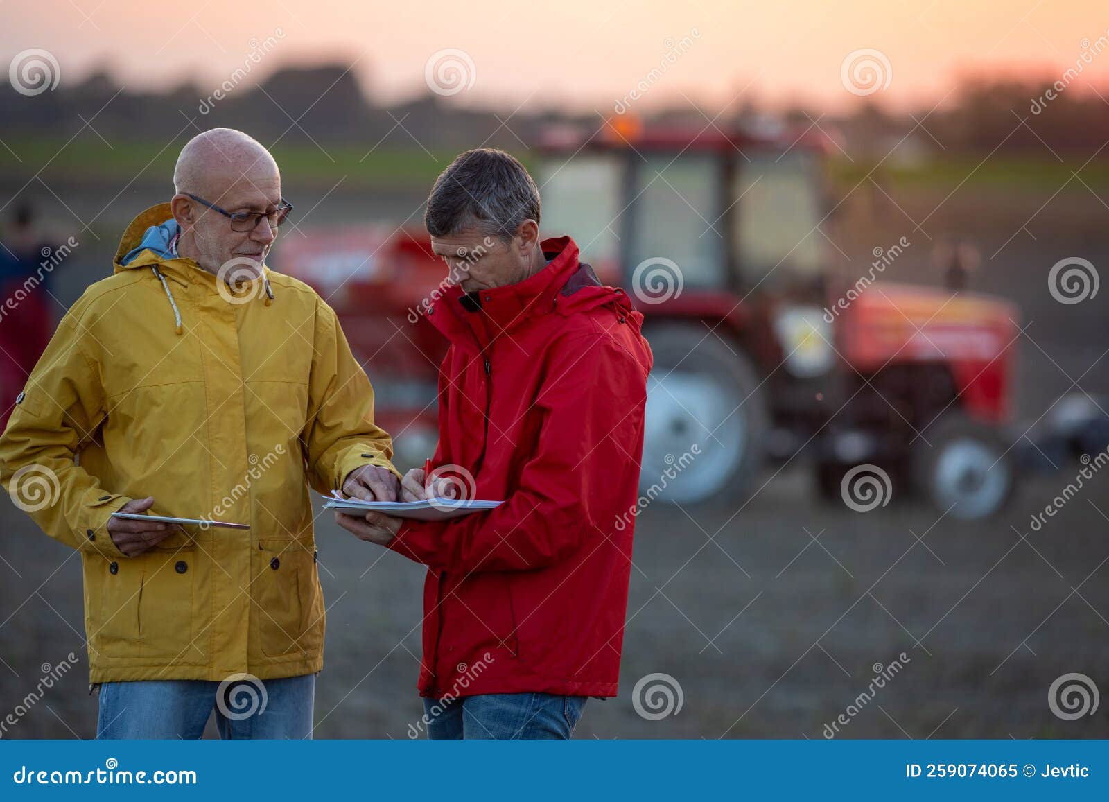 Two Farmers in Field with Tractor in Background Stock Image - Image of ...