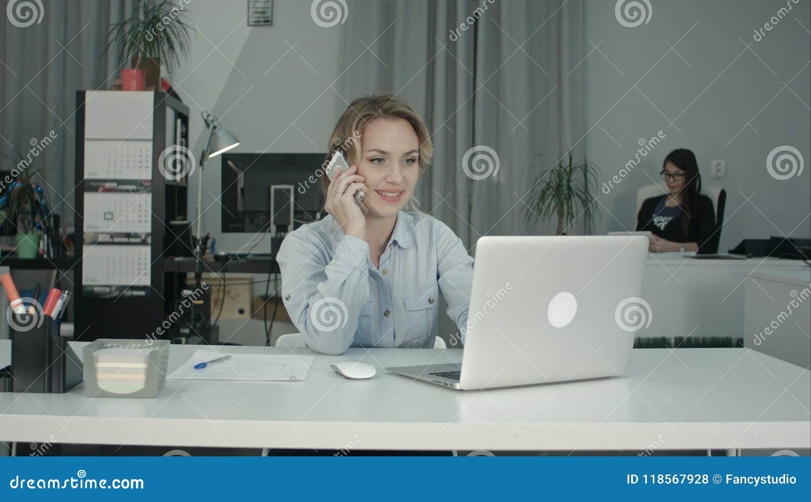 Two Female Coworkers Working Together Answering Phone Calls In The