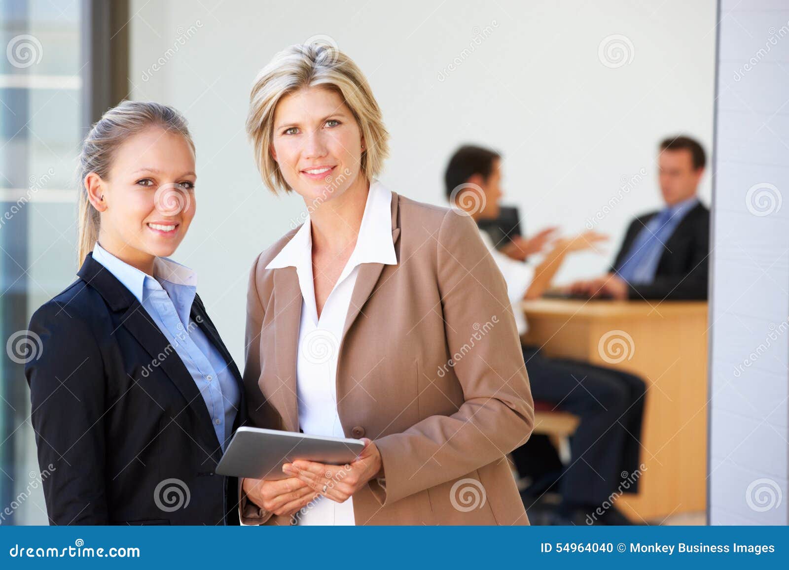 Two Female Executives Using Tablet Computer with Office Meeting in ...
