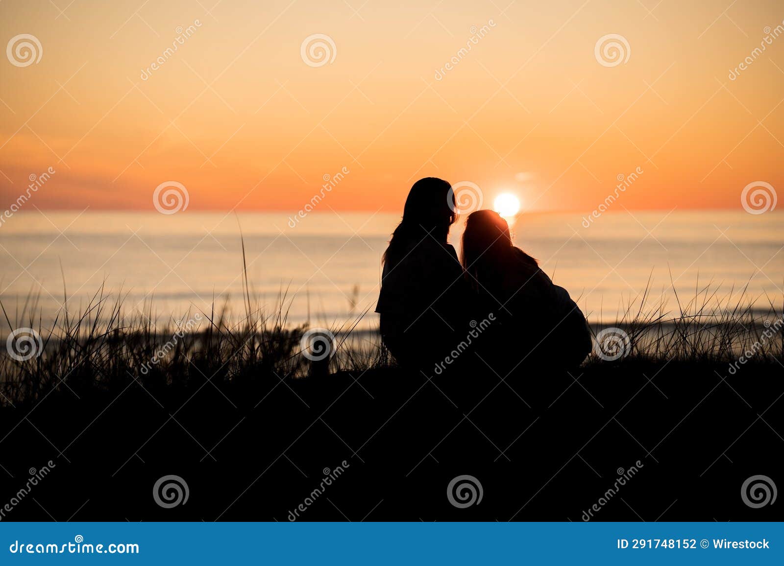 Two Female Friends Enjoying a Conversation while Watching the Sunset on ...