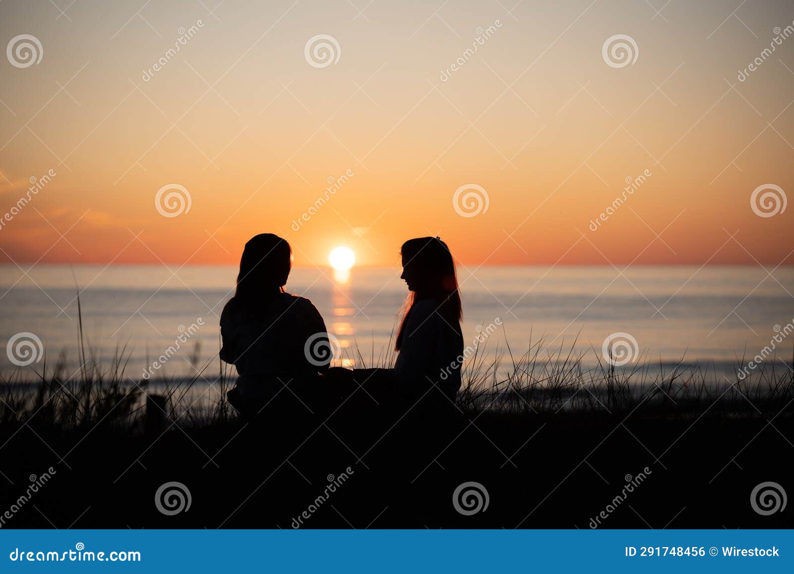 Two Female Friends Enjoying a Conversation while Watching the Sunset on ...