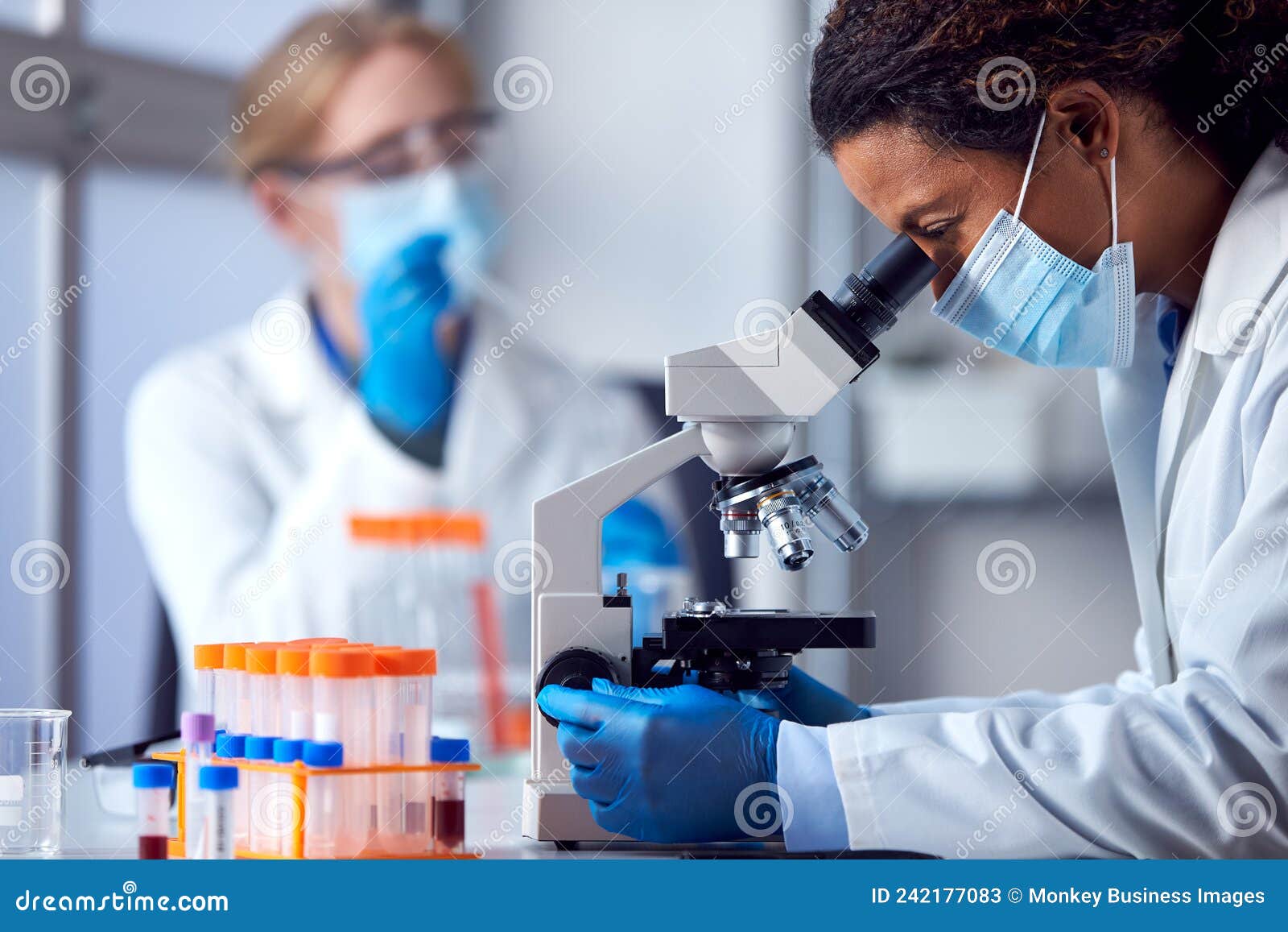 Two Female Lab Workers Wearing PPE and Safety Glasses Looking at Slide ...
