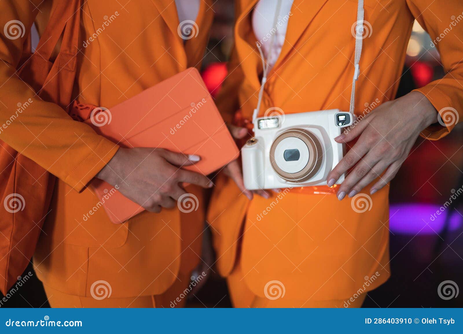 Two Female Promoters in Identical Suits with a Camera and a Tablet ...