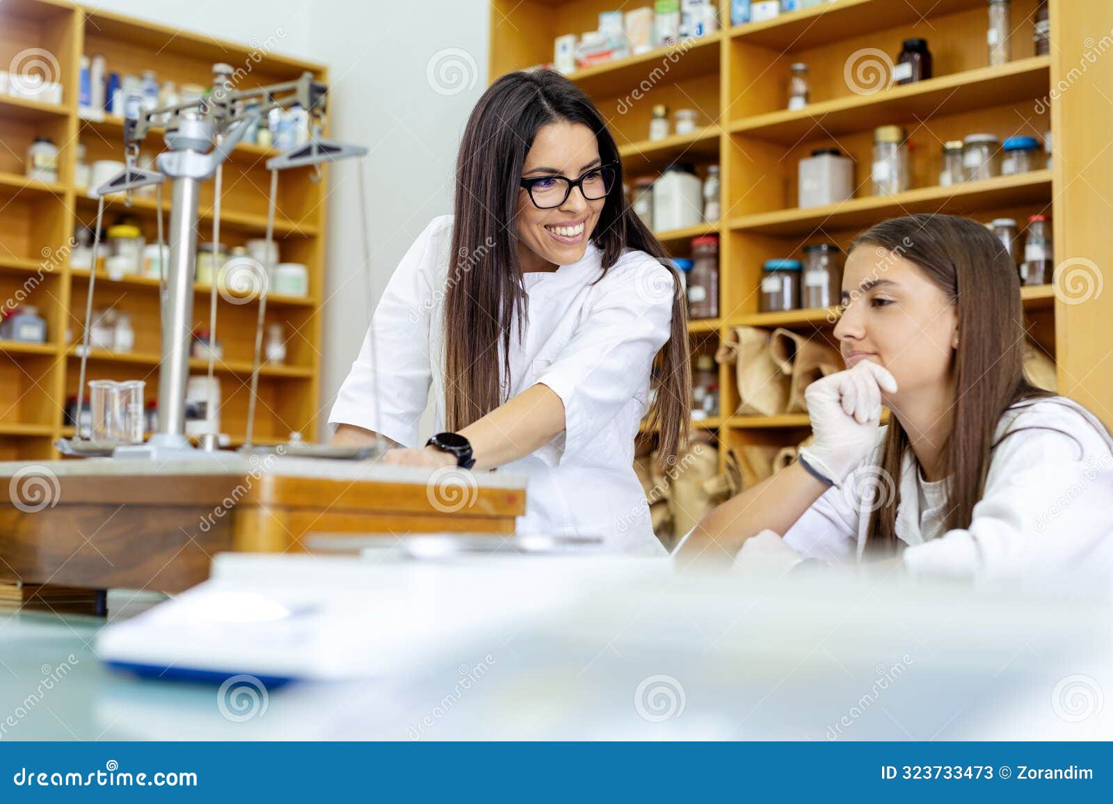 Two Female Scientists Dressed in White Lab Coats Work Together. Stock ...