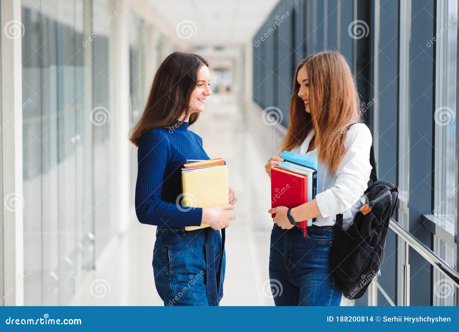 Two Female Students Stand in the Corridor of the College with Books ...