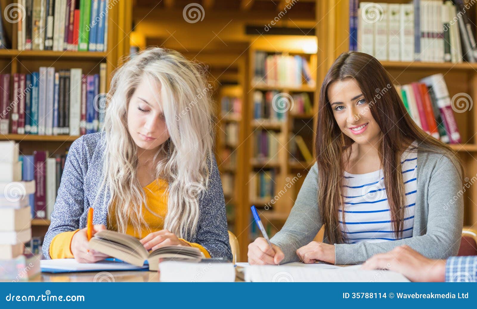 Two Female Students Writing Notes at Library Desk Stock Photo - Image ...