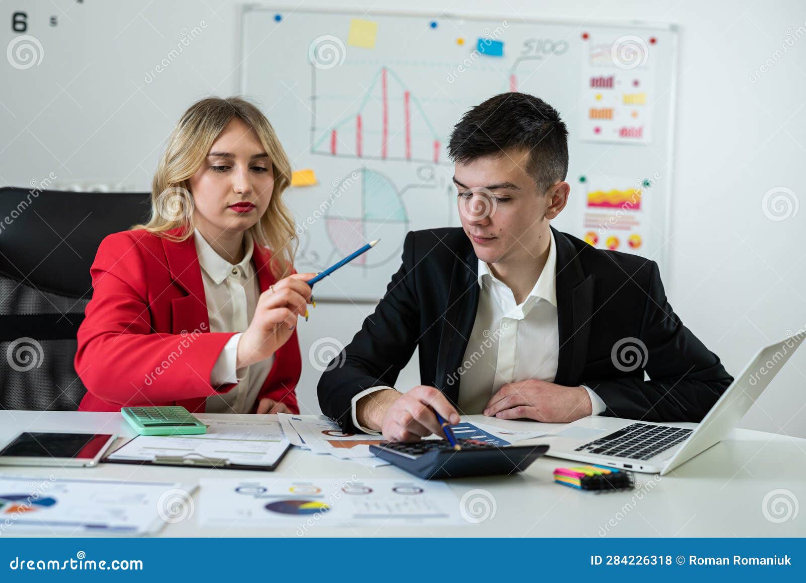 Two Financial Analysts Working Together with Paper Charts and Laptops ...