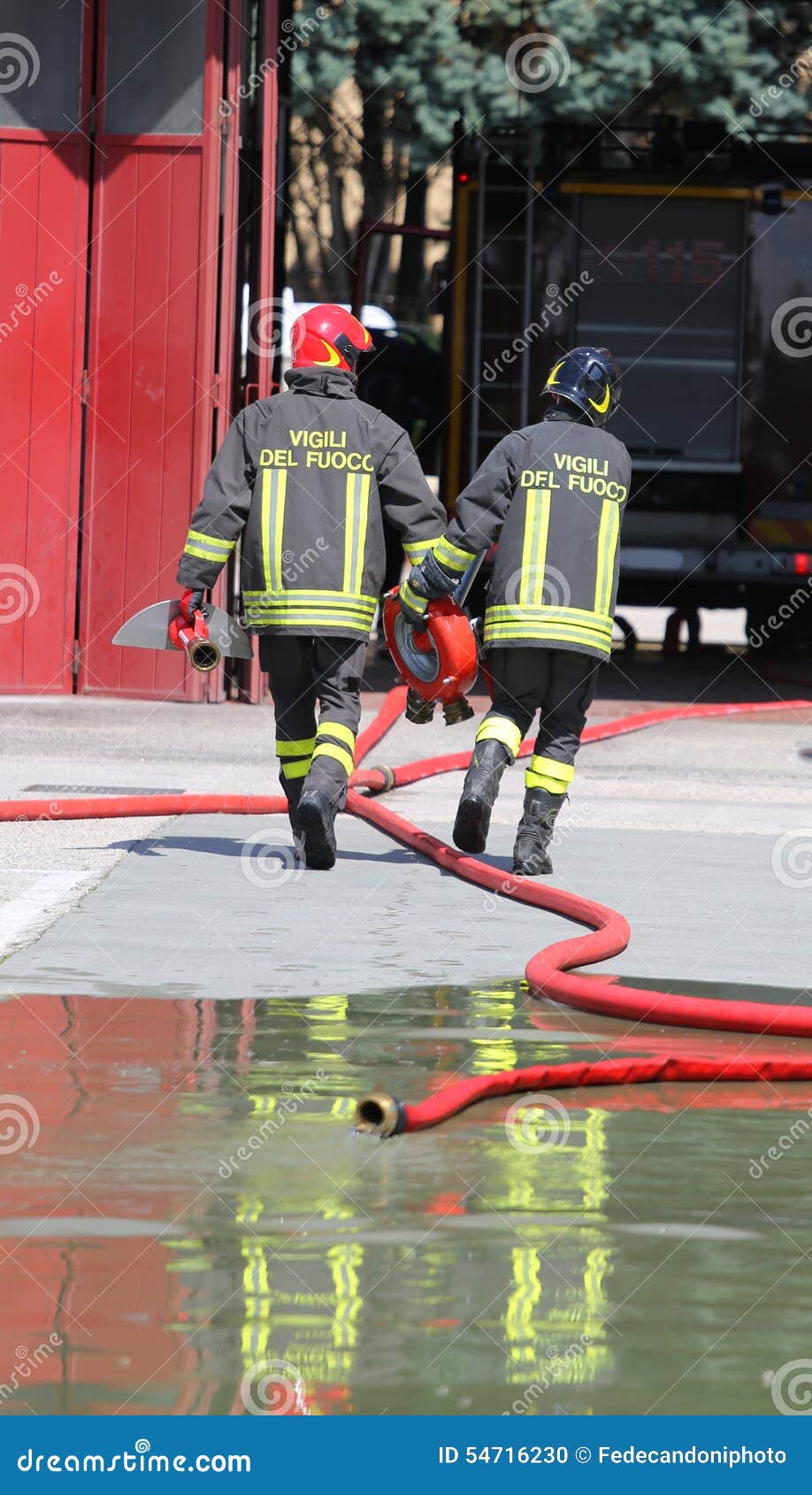Two Firefighters Carry the Hydrant and Hose Pipes Stock Photo - Image ...