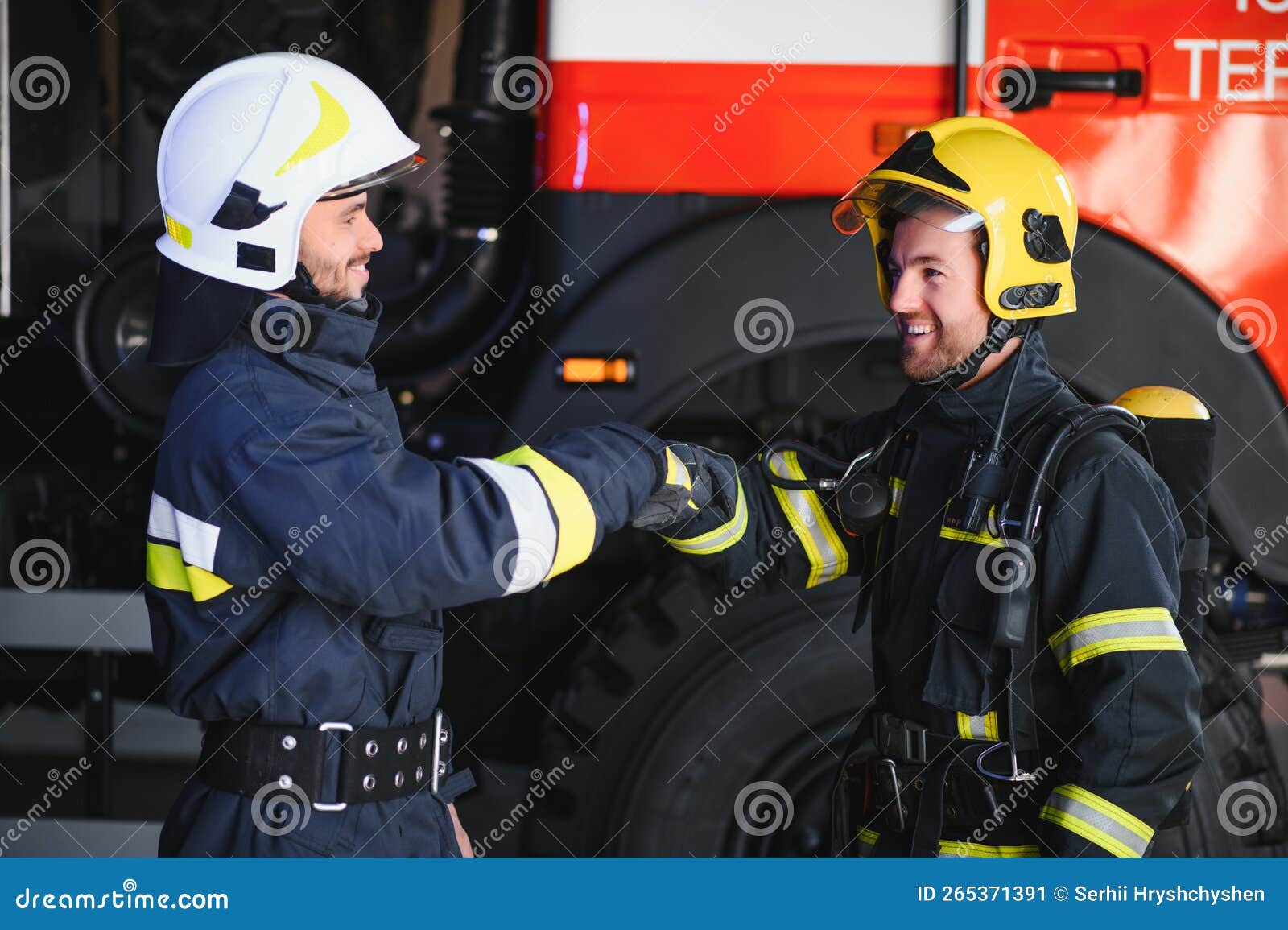 Two Firefighters in Protective Clothing in Helmets with Fire Engine ...