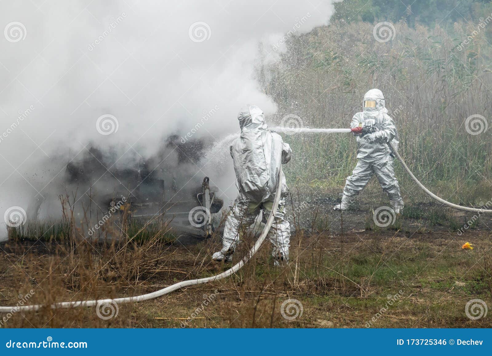 Two Firefighters in Protective Suits Works with Water Hose. Fighting ...