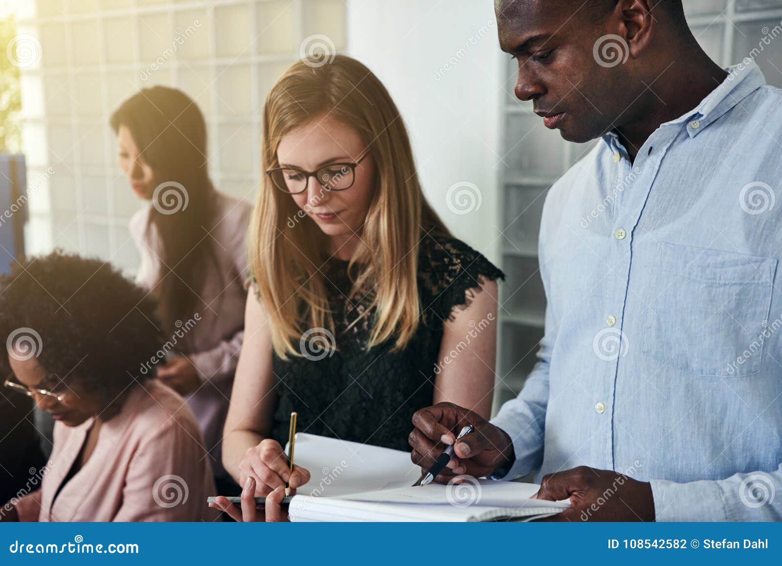 Two Focused Colleagues Comparing Notes Together in a Modern Office ...