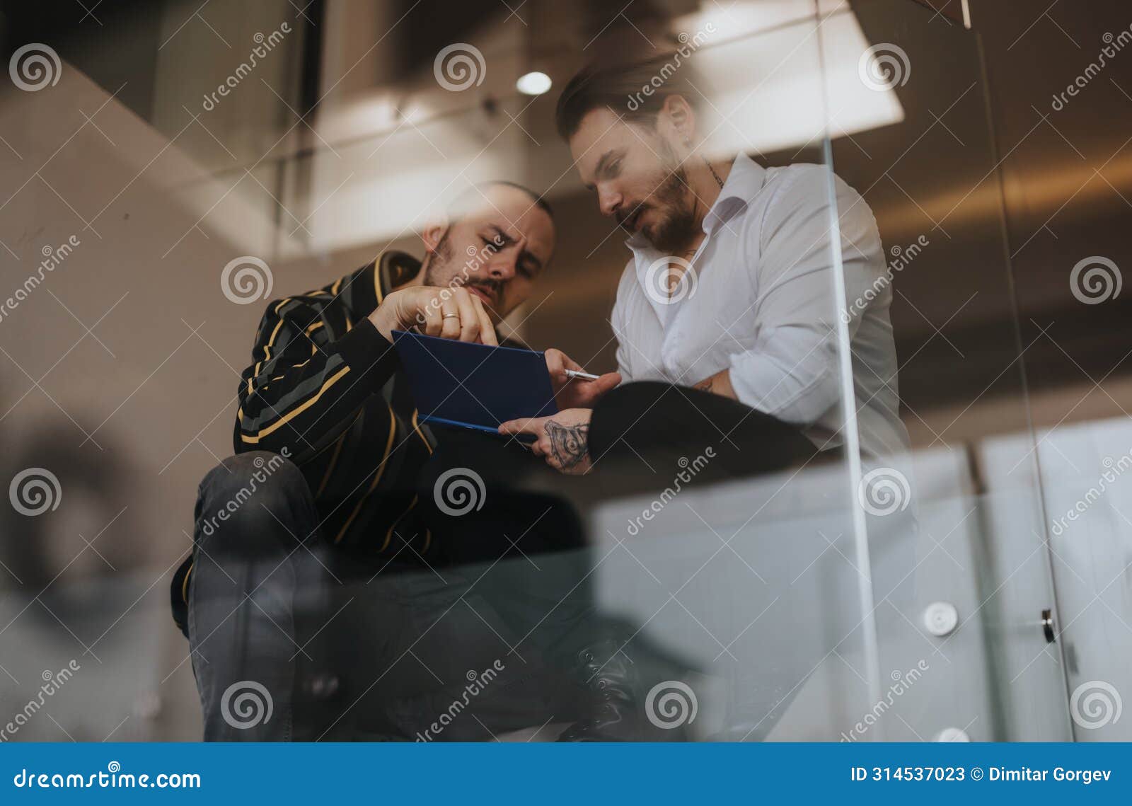 Two Focused Men Collaborating while Looking at Notes in a Modern Office ...