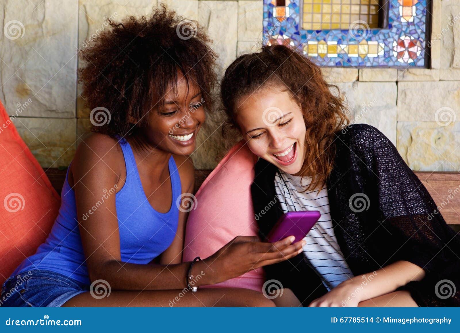 Two Friends Laughing and Looking at Mobile Phone Stock Photo - Image of ...