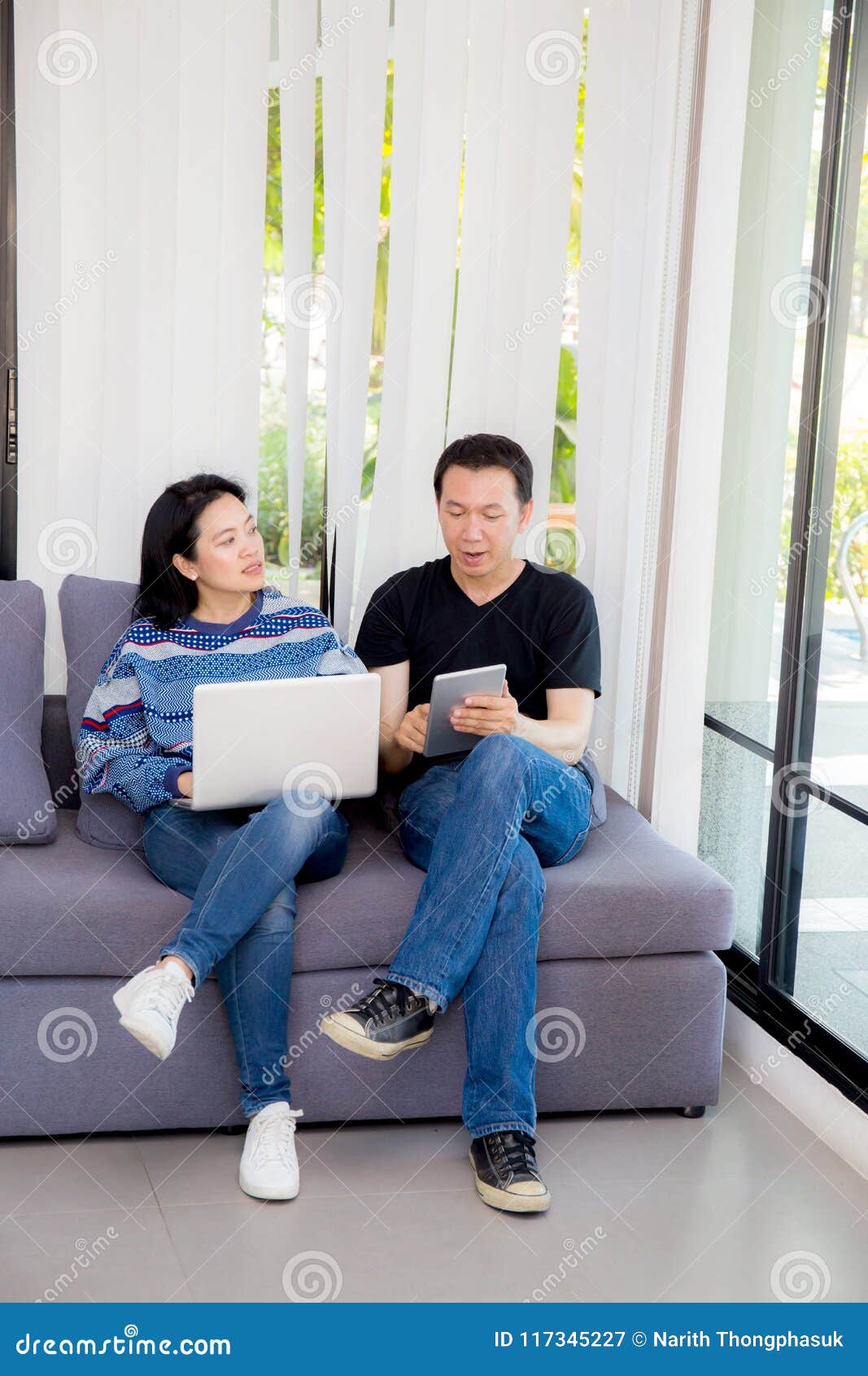 Two Friends on Line with Multiple Devices and Talking Sitting on a Sofa ...