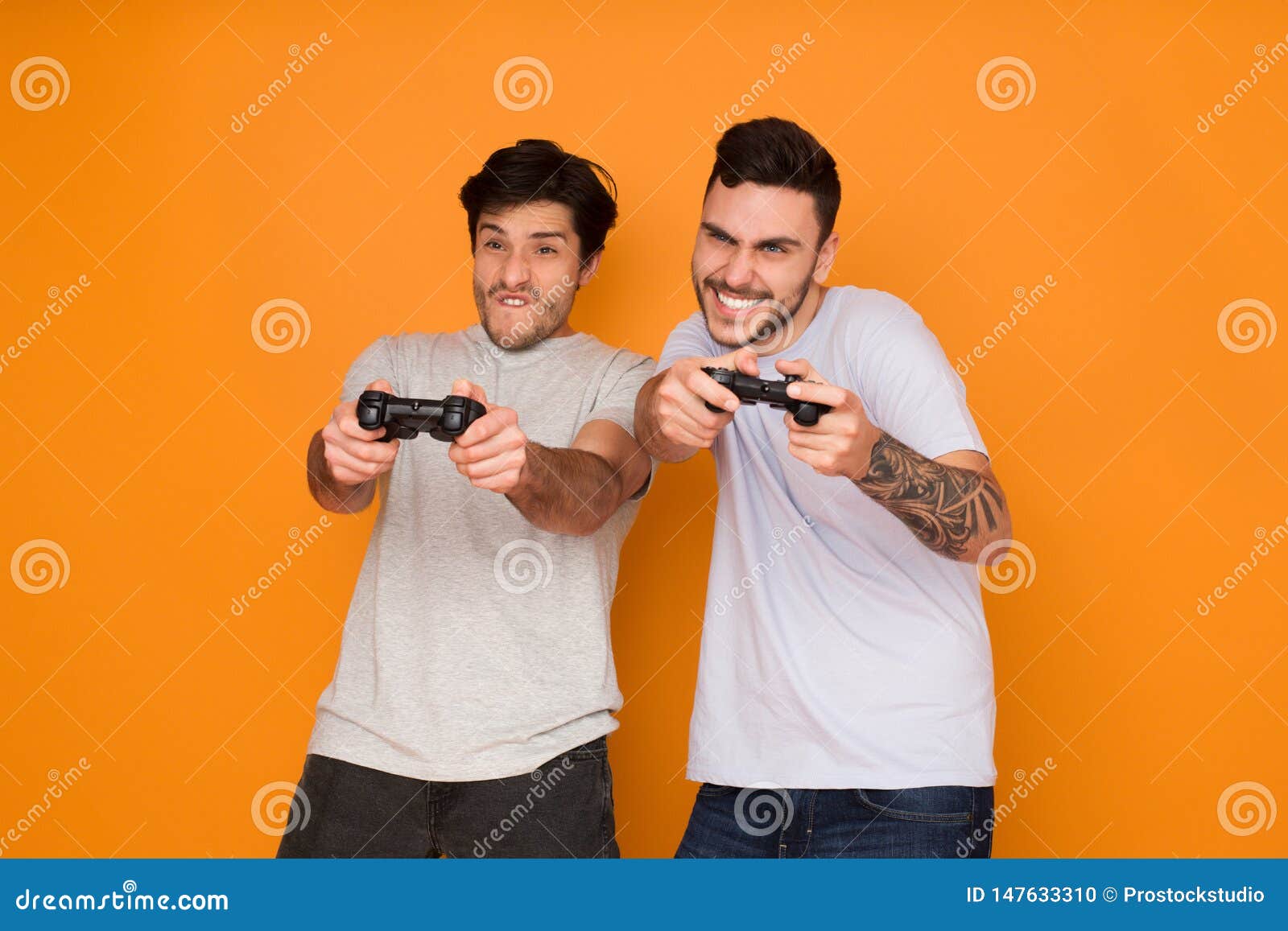 Two Friends Playing Video Games Over Orange Background Stock Photo ...