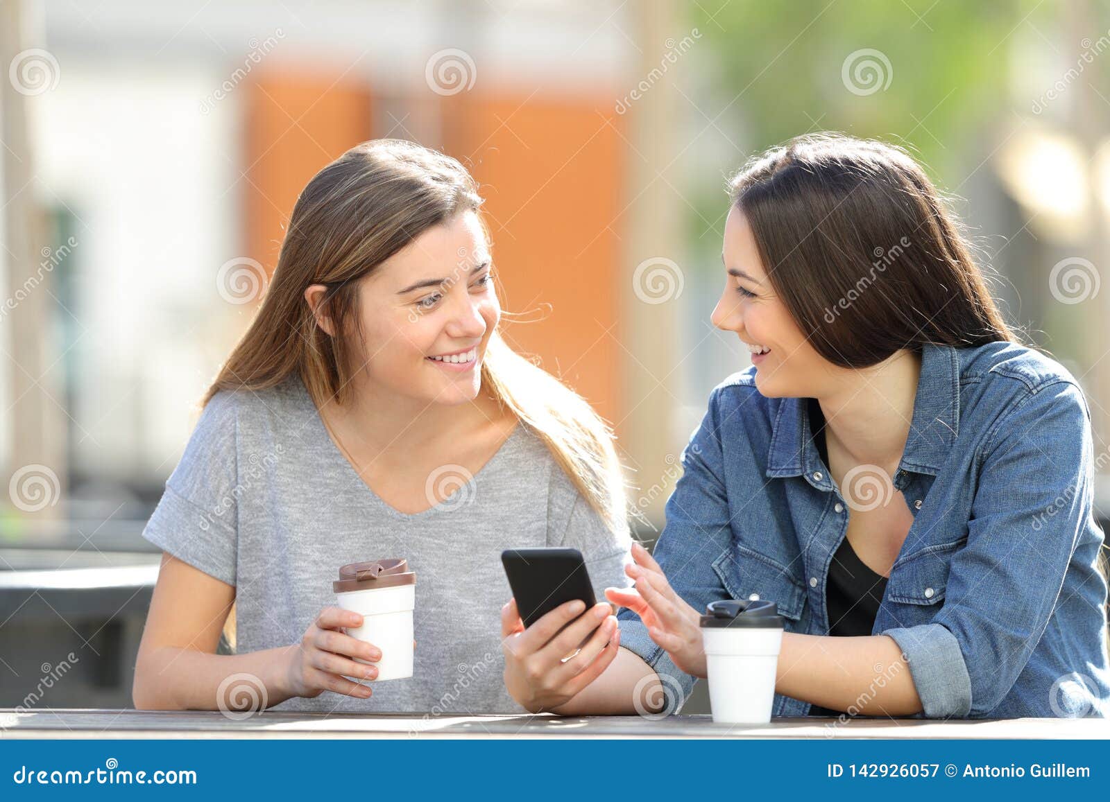 Two Friends Talking about Phone Content in a Park Stock Image - Image ...