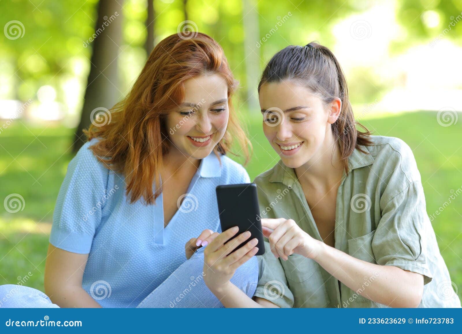 Two Friends Watching Phone Content in a Park Stock Image - Image of ...