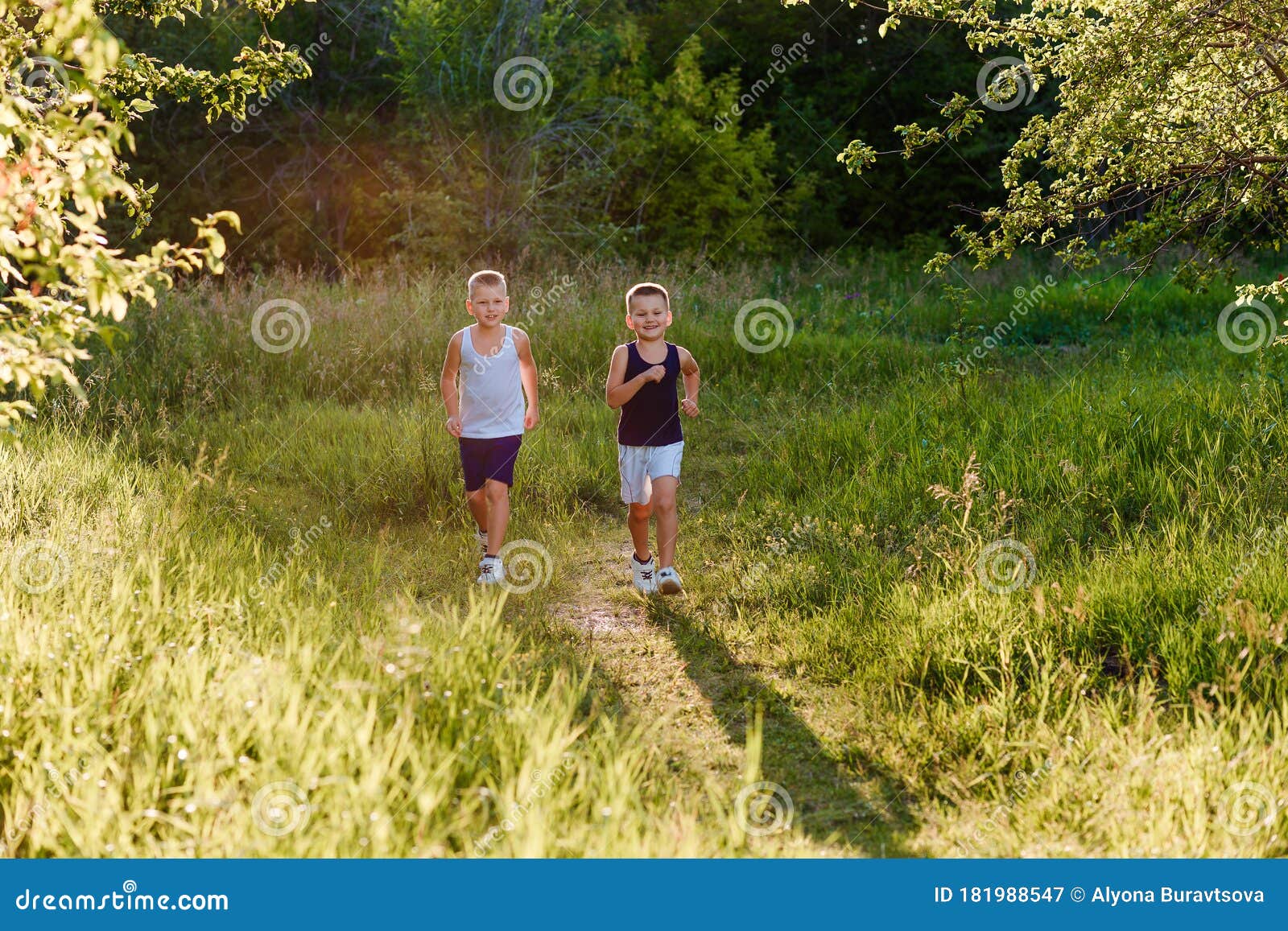 Two Boys Run through the Park in the Windlight in the Summer Stock ...