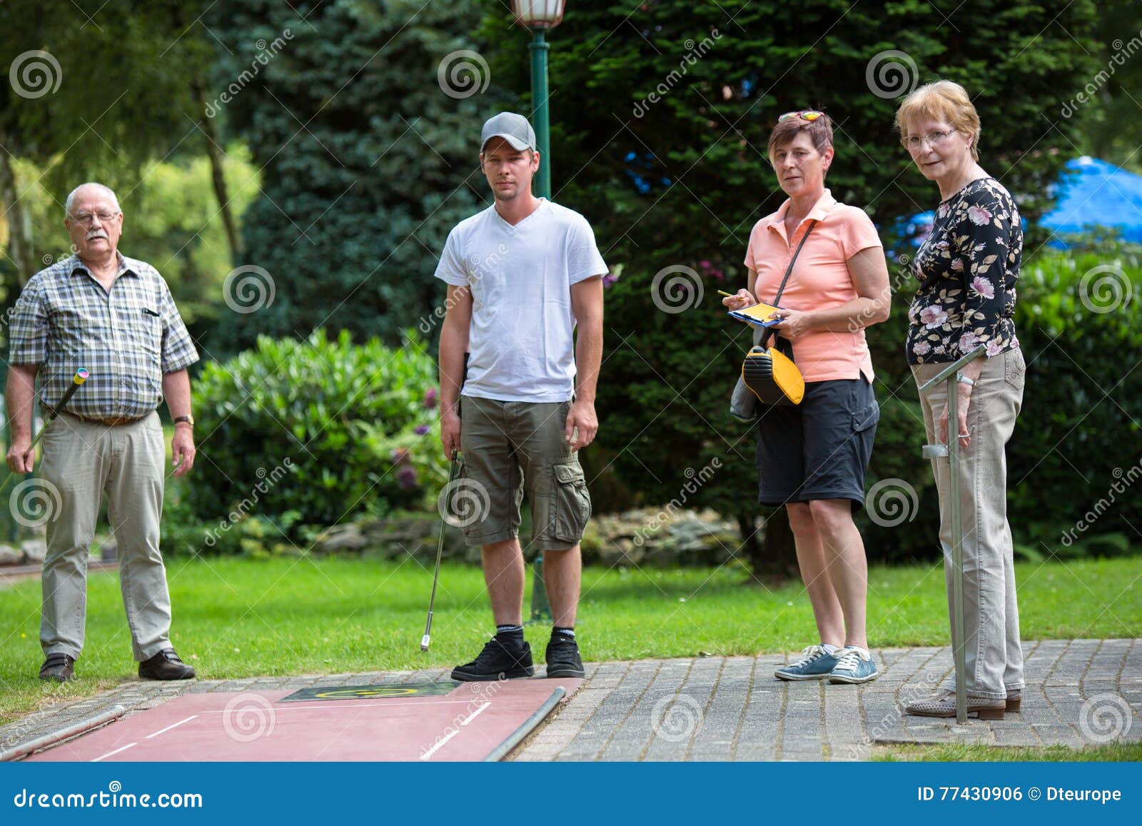 Two Generation of People are Playing Minigolf Together at a Sunny Day ...