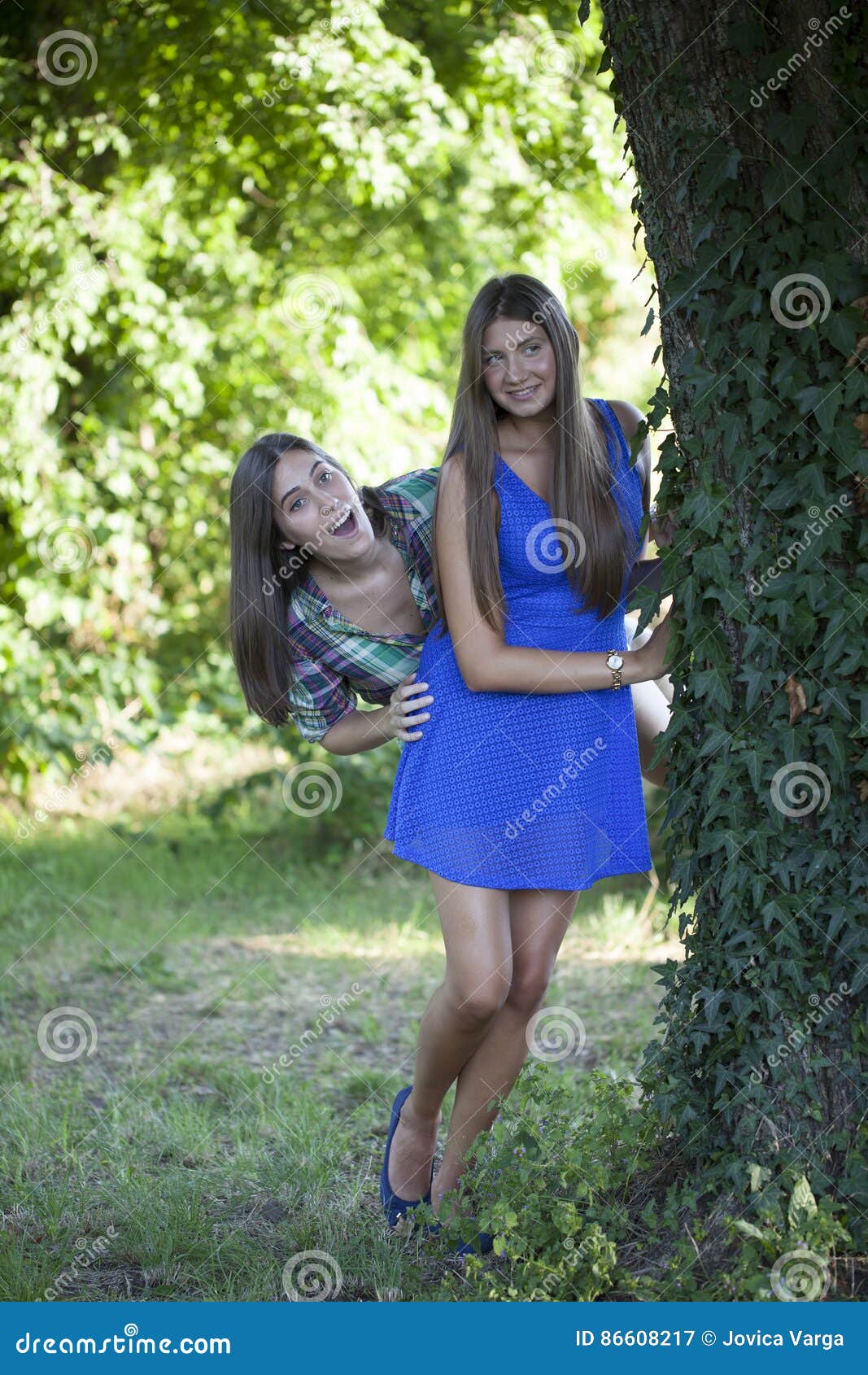 Two girls behind a tree stock image. Image of nature - 86608217