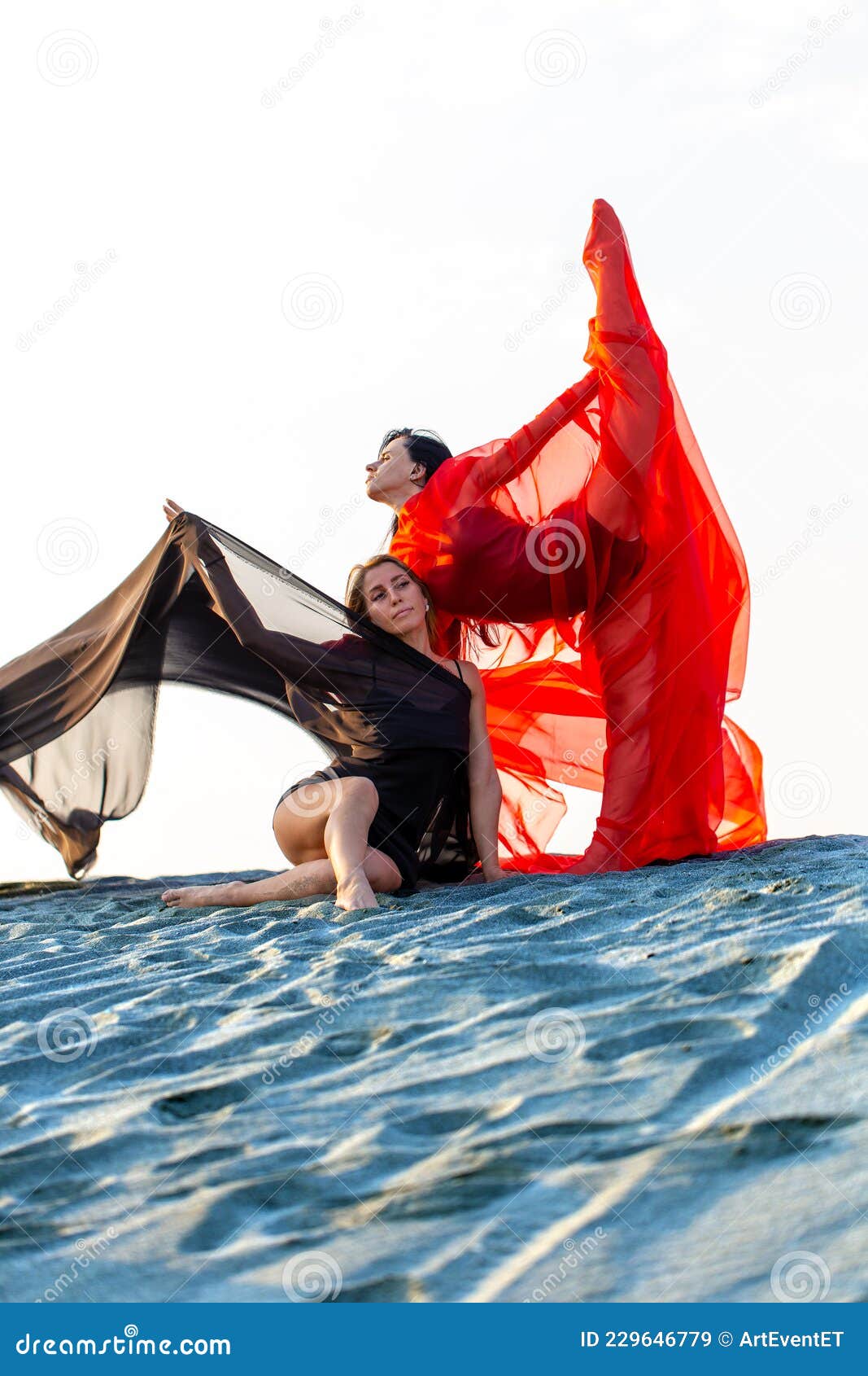 Two Girls with Black and Red Fluttering Cloth Dancing on the Sand Dune ...