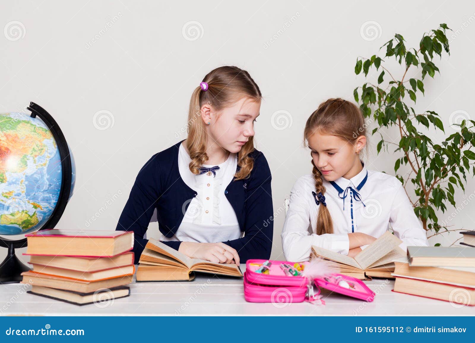 Two Girls with Books and a Globe in Class at the Desk at School Stock ...