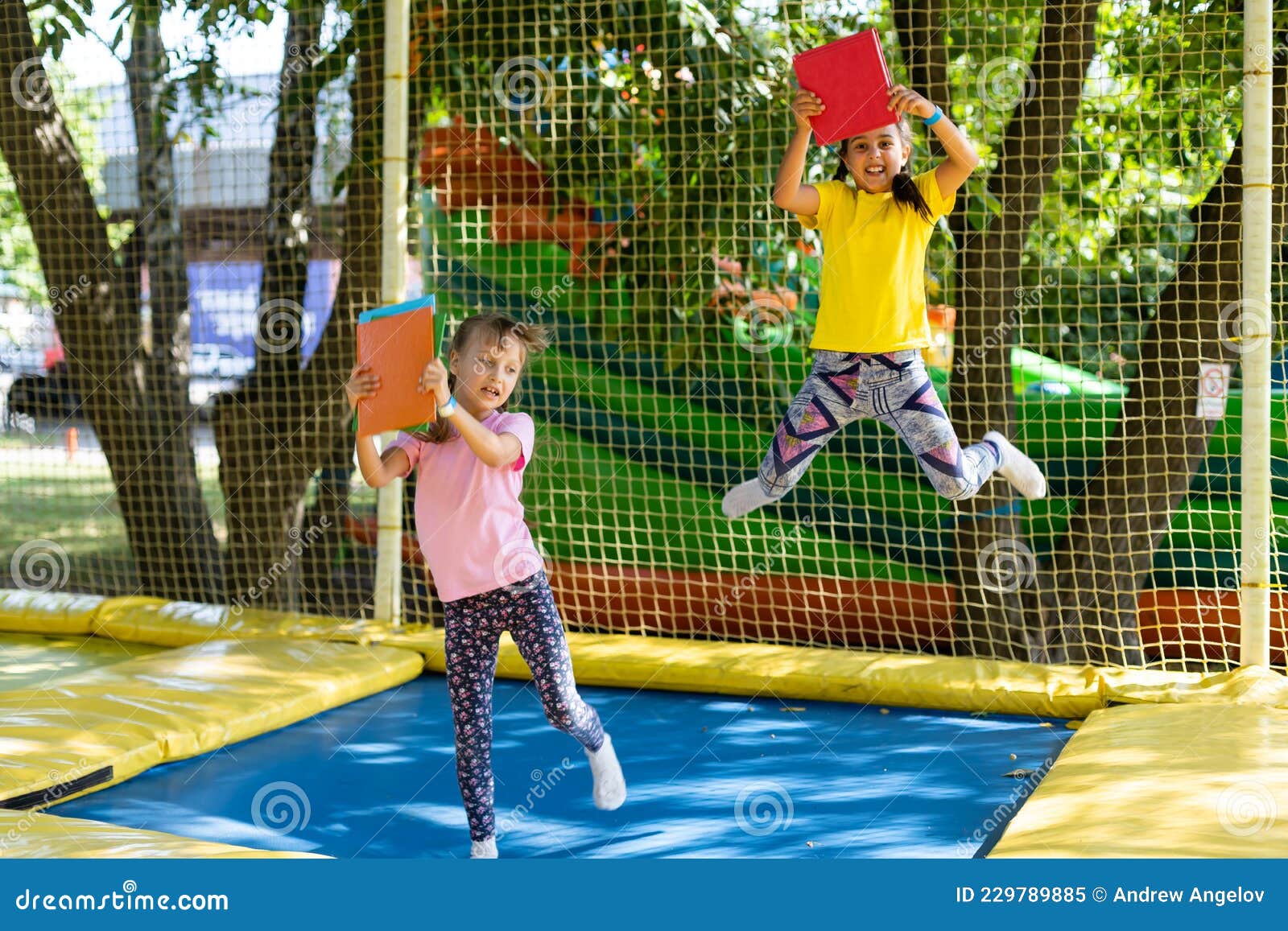 Two Girls with Books Jump on a Trampoline. Stock Image - Image of ...