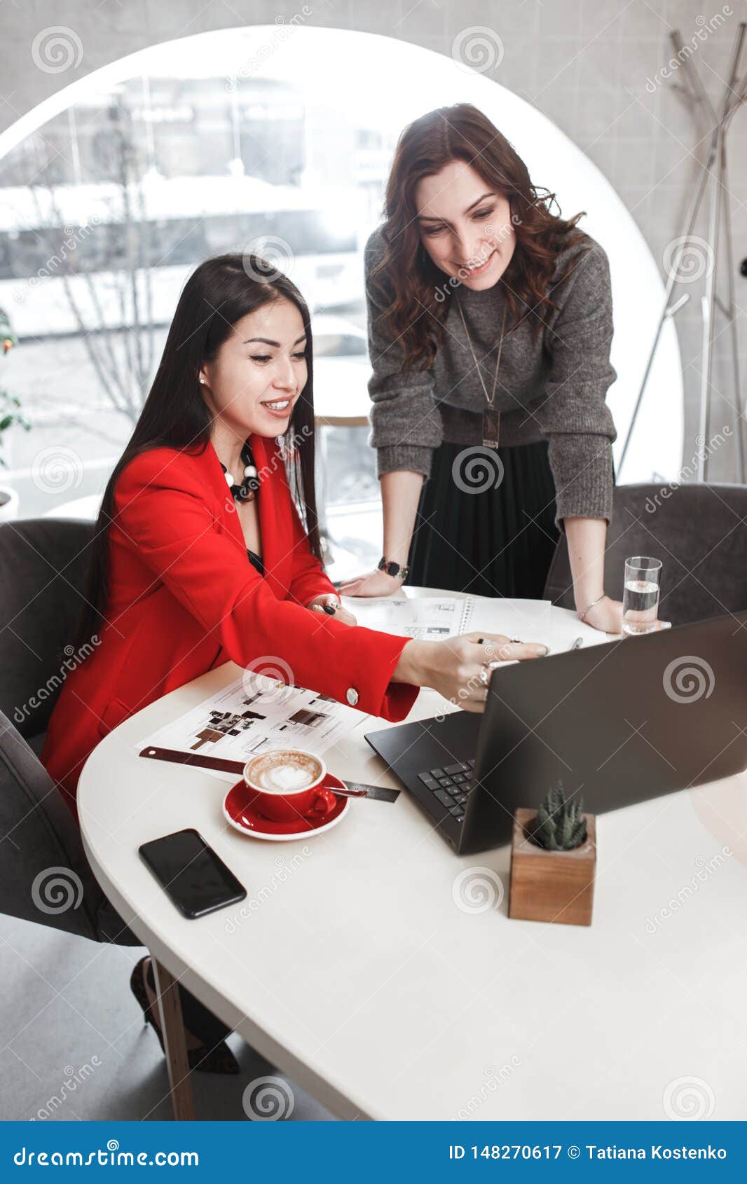 Two Girls Designers are Working with Laptop and Documentation at the ...