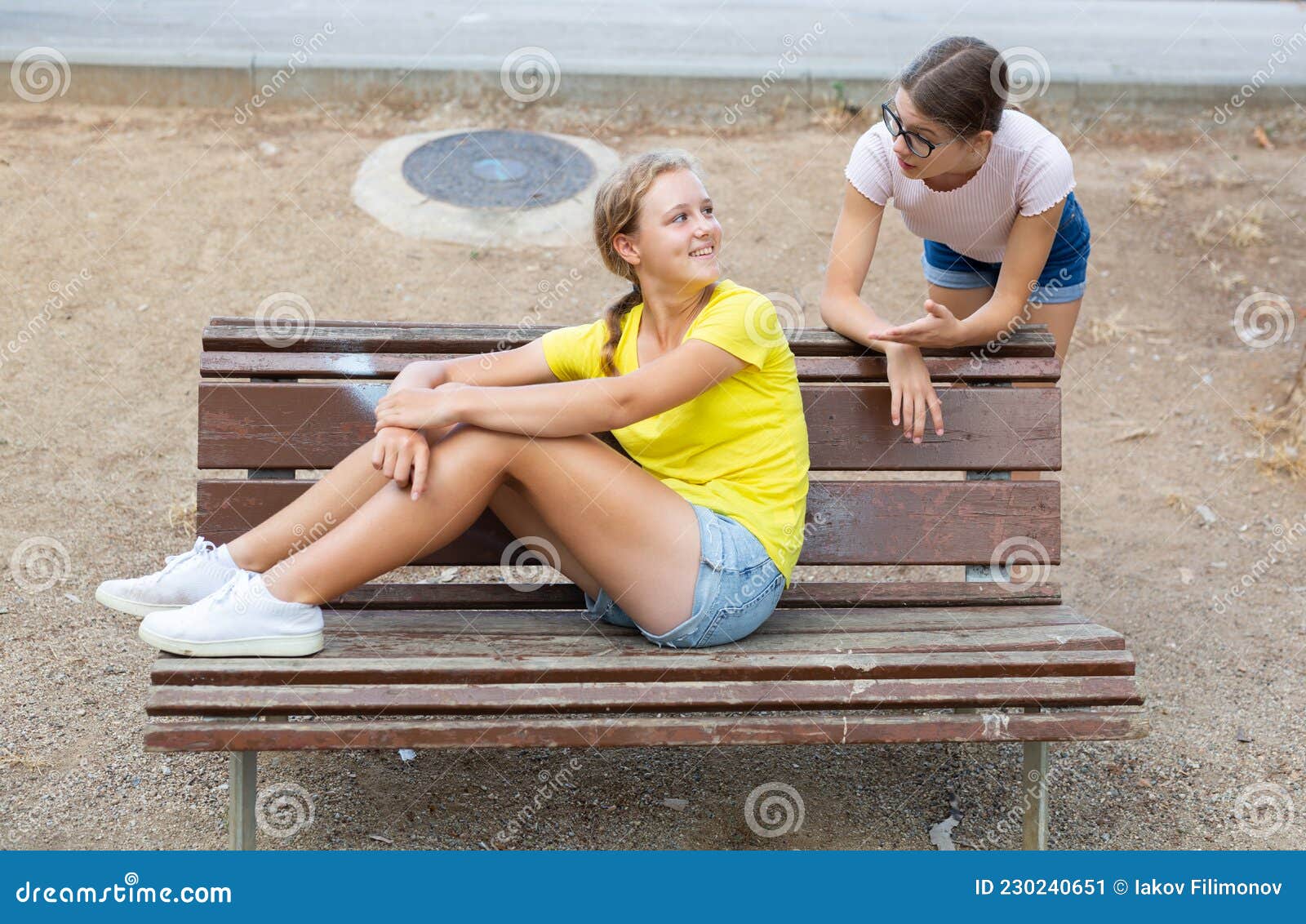 Two Girls Friends Sitting on Bench in Summer Park Chatting Happily ... Two Girls Friends Sitting on Bench in Summer Park Chatting Happily ...