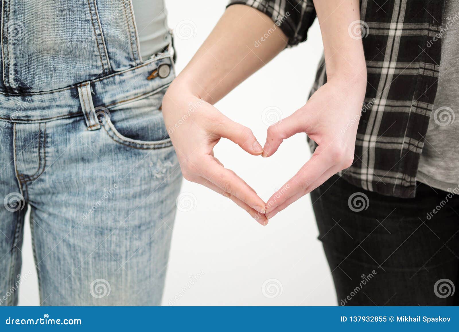 Two Girls In Jeans Hold Hands Close Up White Background Homosexual