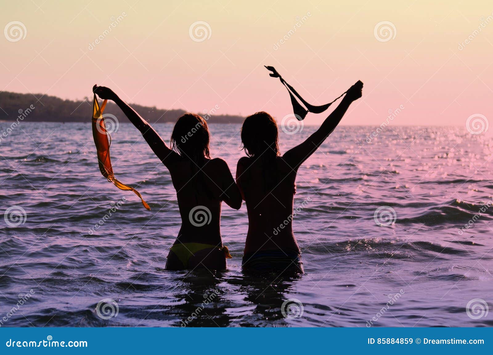 Two girls in ocean stock image. Image of swimsuit, silhouette - 85884859