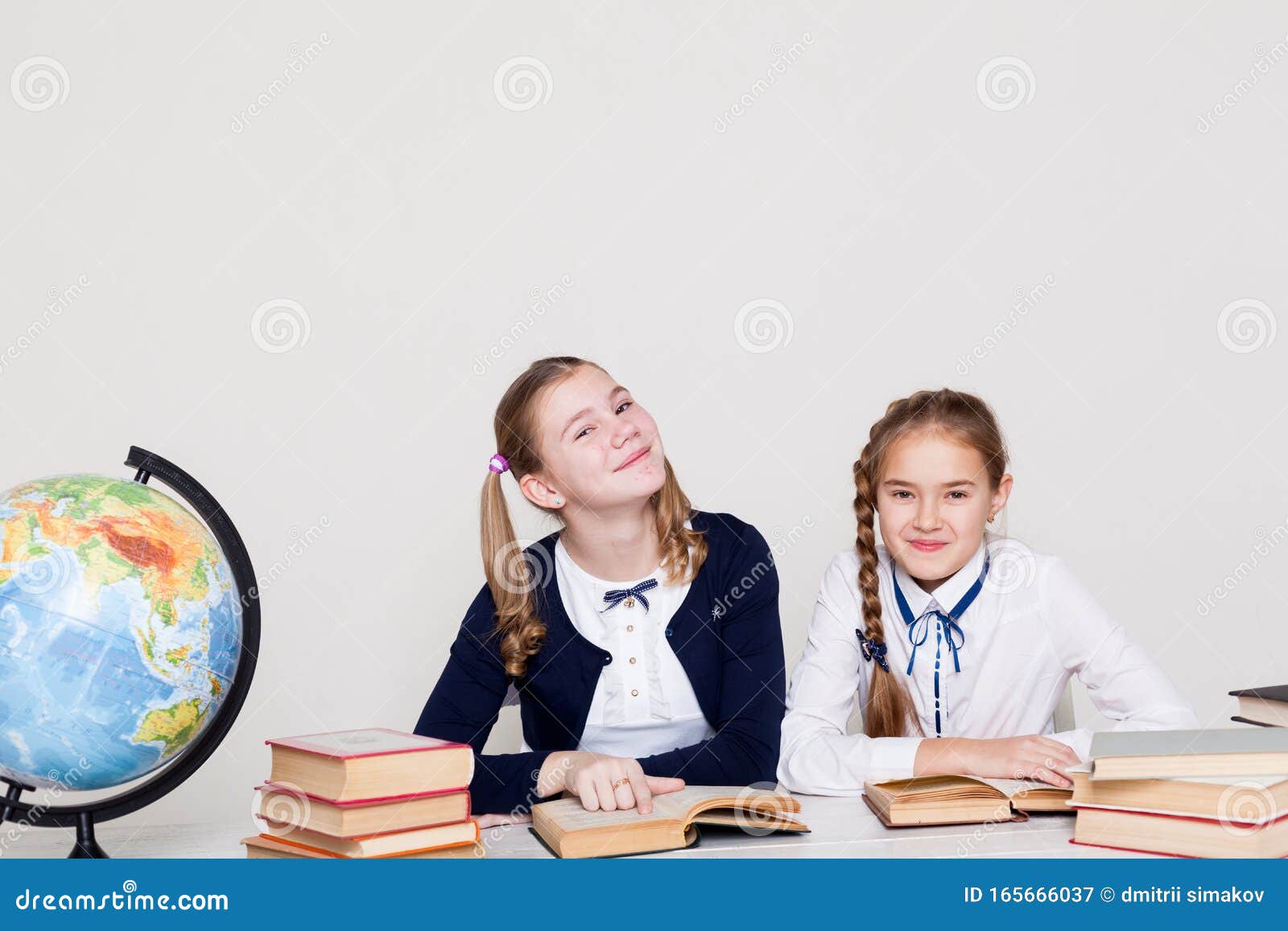Two Girls of the School with Books for Studying Sit at the Desk in the ...