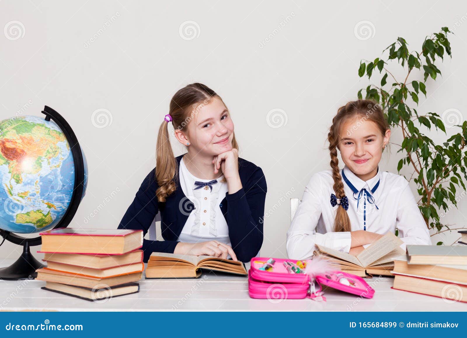 Two Girls of the School with Books for Studying Sit at the Desk in the ...