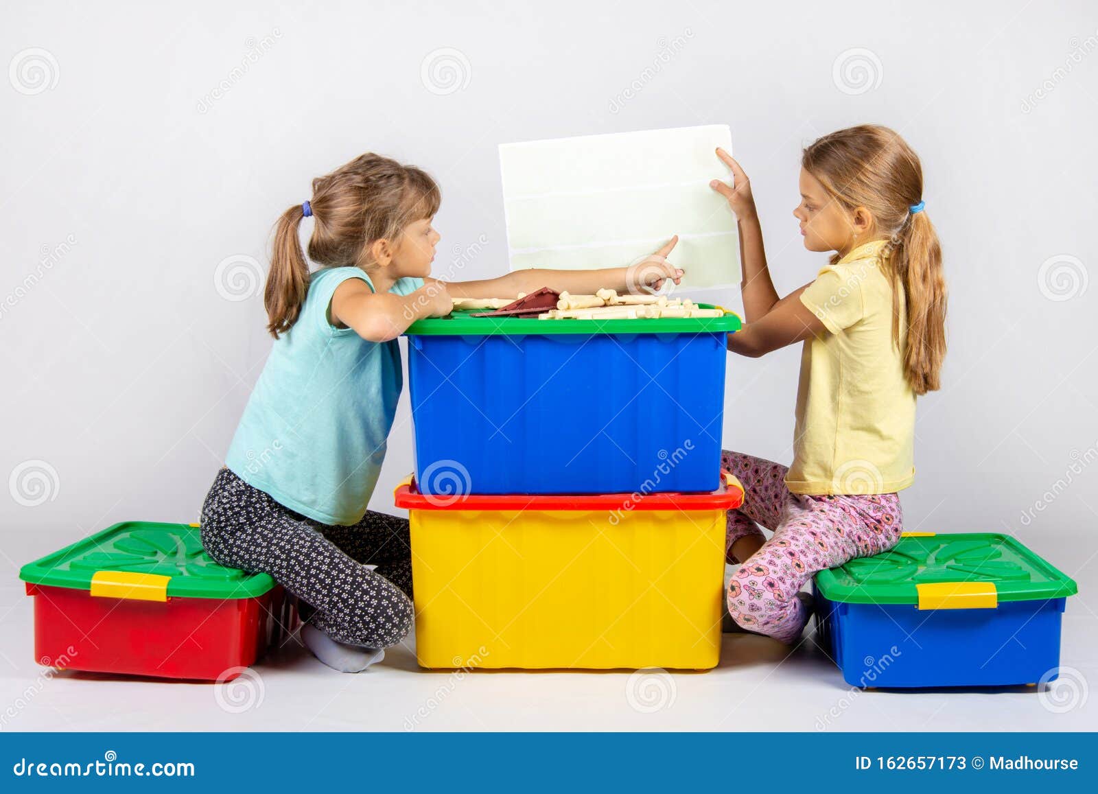 Two Girls Sit on Large Toy Boxes and Look at the Toy Assembly ...