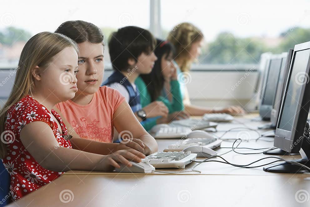 Two Girls (10-12) Using Computer in Computer Lab Children in Background ...