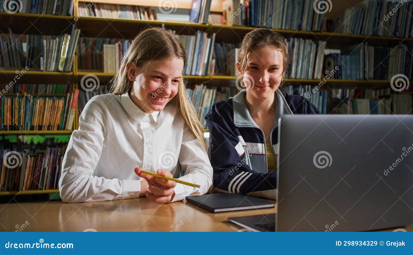 Two Girls Using a Laptop during Online Lessons in the Library Stock ...