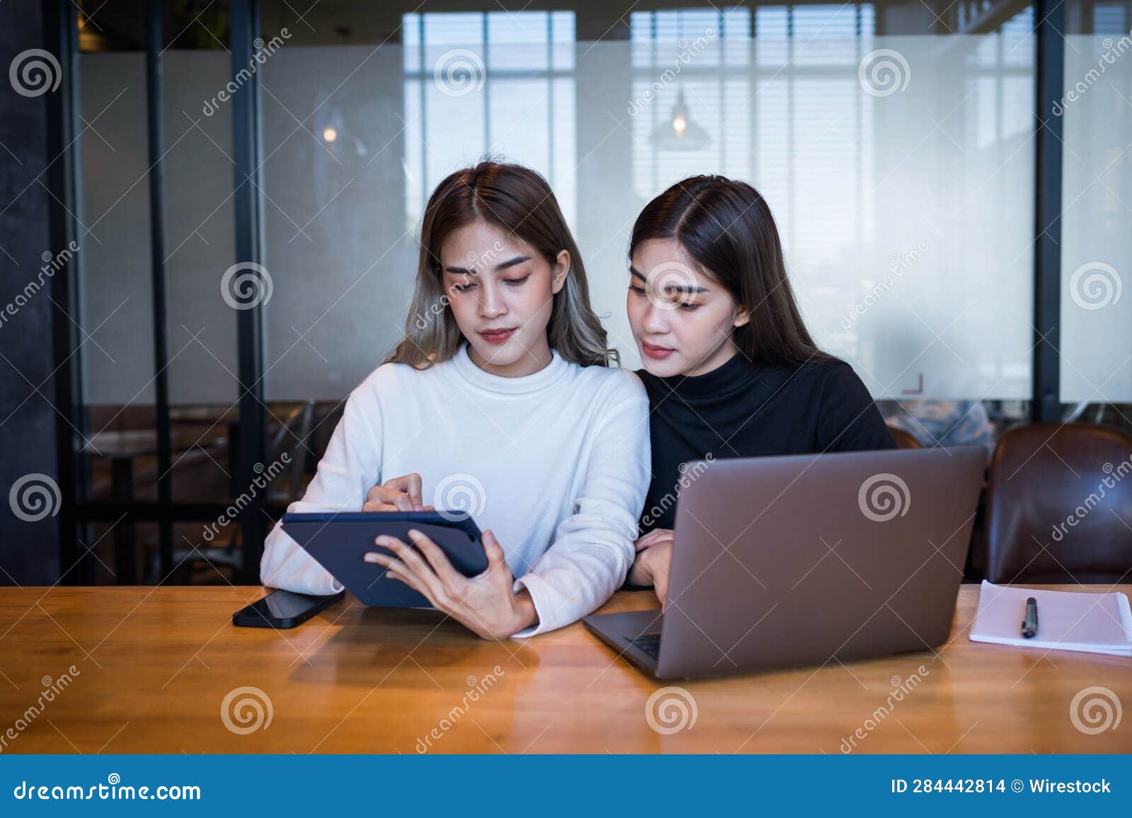 Two Girls Using Their Tablet and Computer in a Meeting Room Stock Photo ...