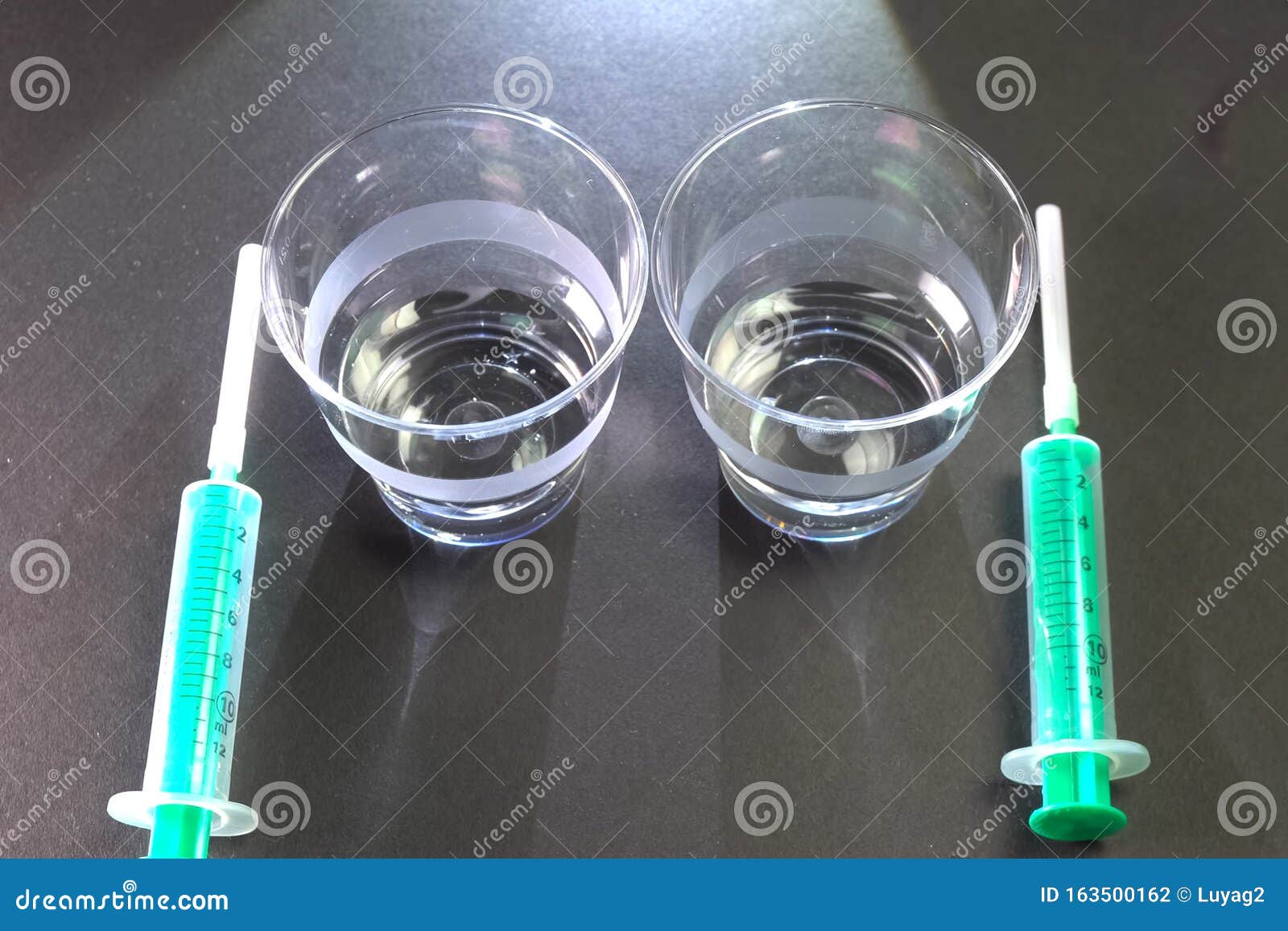 Two Glasses of Water and Two Syringes on Table Stock Photo - Image of ...