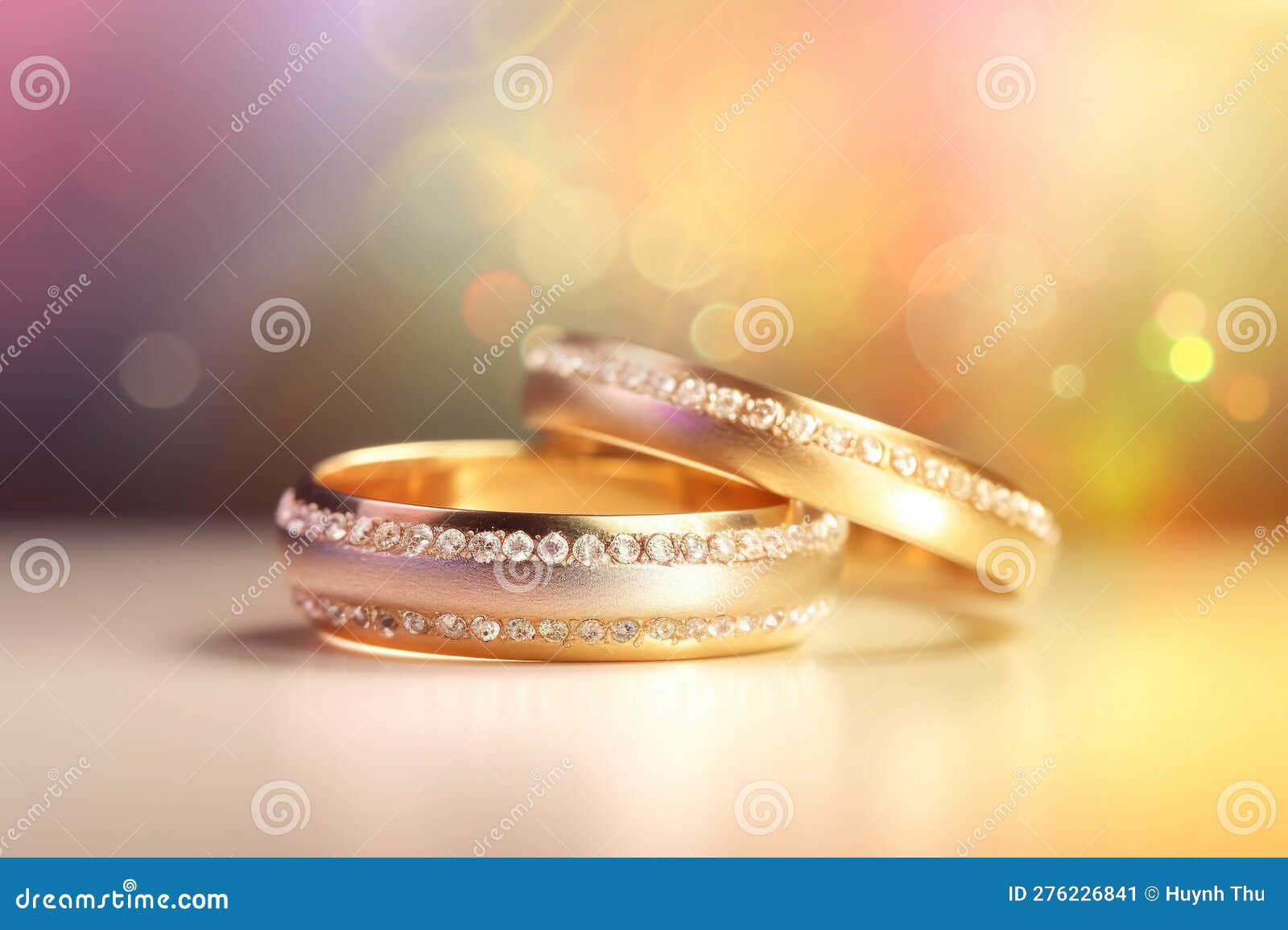 Two Gold Wedding Rings are in Front of a Pastel Bokeh Background, in ...