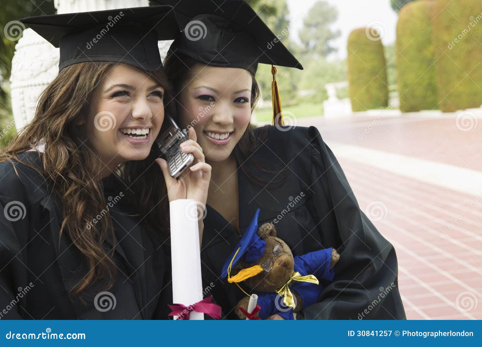 Two Graduates Using Cell Phone Outside Stock Image - Image of 2025 ...