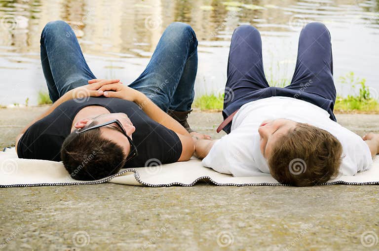 Two Guys Relaxing Alongside a River Stock Image - Image of adult, guys ...