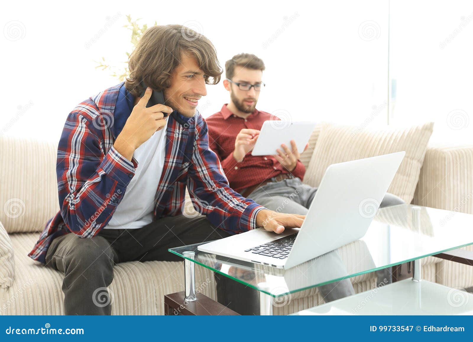 Two Guys Sitting on the Couch, Talking on a Mobile Phone and Chatting ...