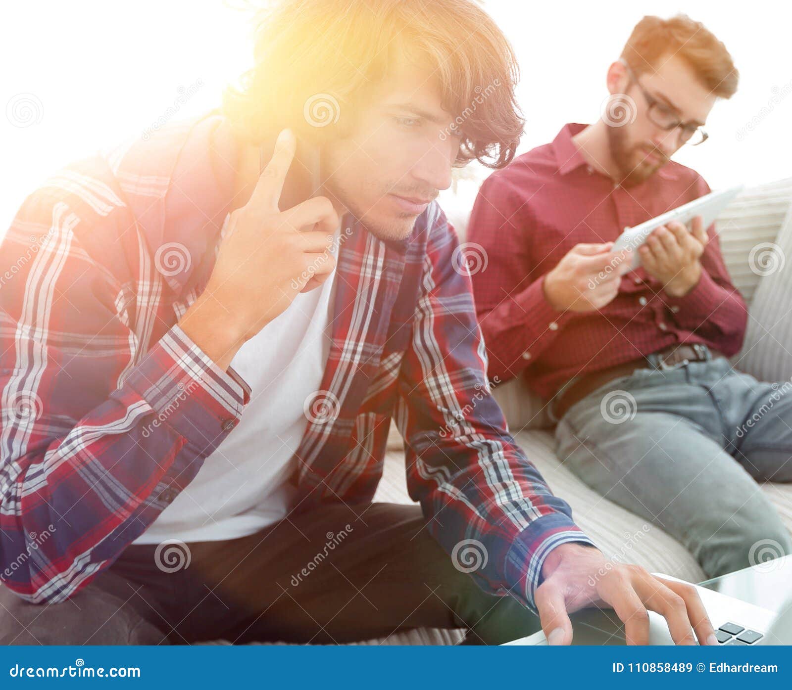 Two Guys Sitting on the Couch, Talking on the Smartphone and ...