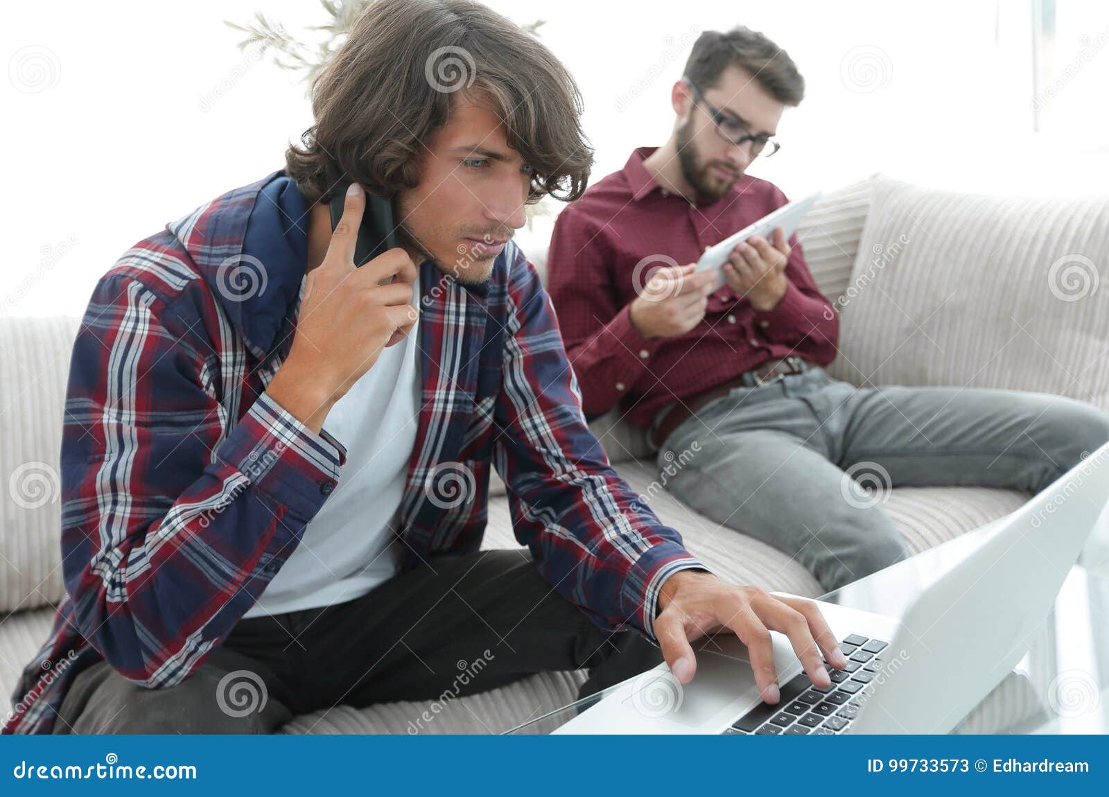 Two Guys Sitting on the Couch, Talking on the Smartphone and ...