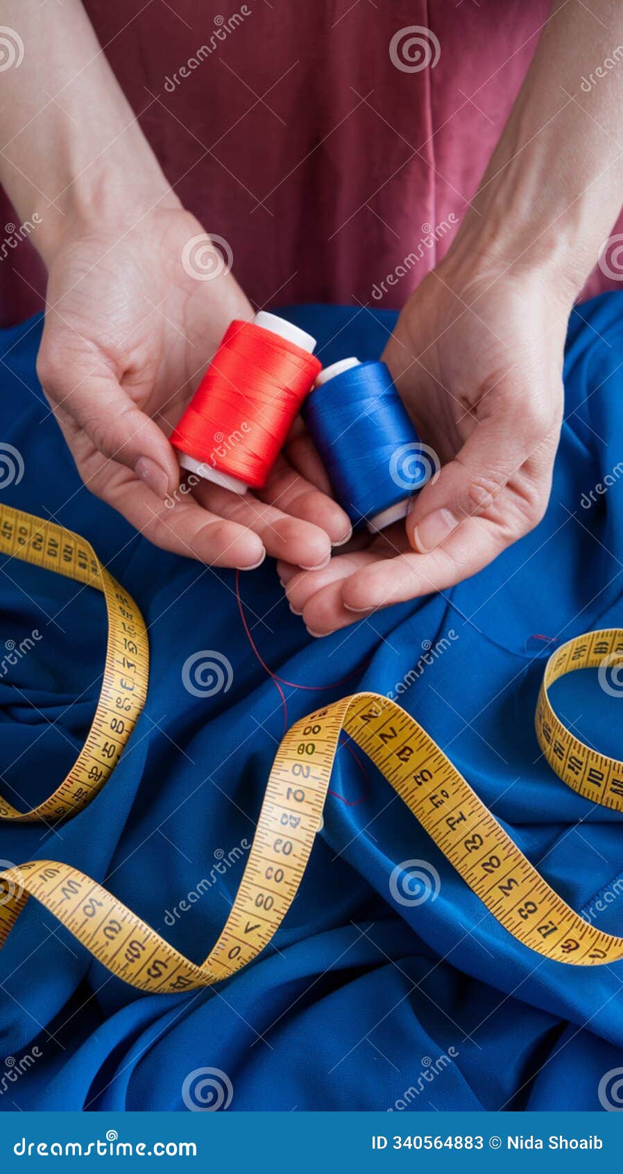 Two Hands Holding Thread Spools on Blue Fabric, Measuring Tape Creates ...