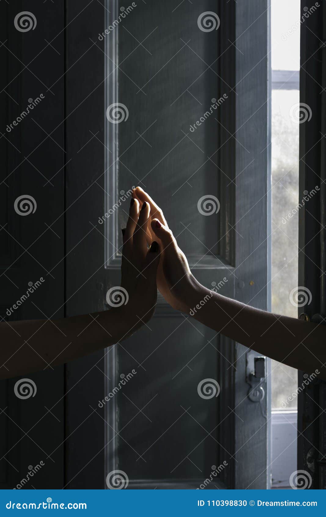 Two Hands Touching Each Other in Front of a Blue Window Illuminated by ...