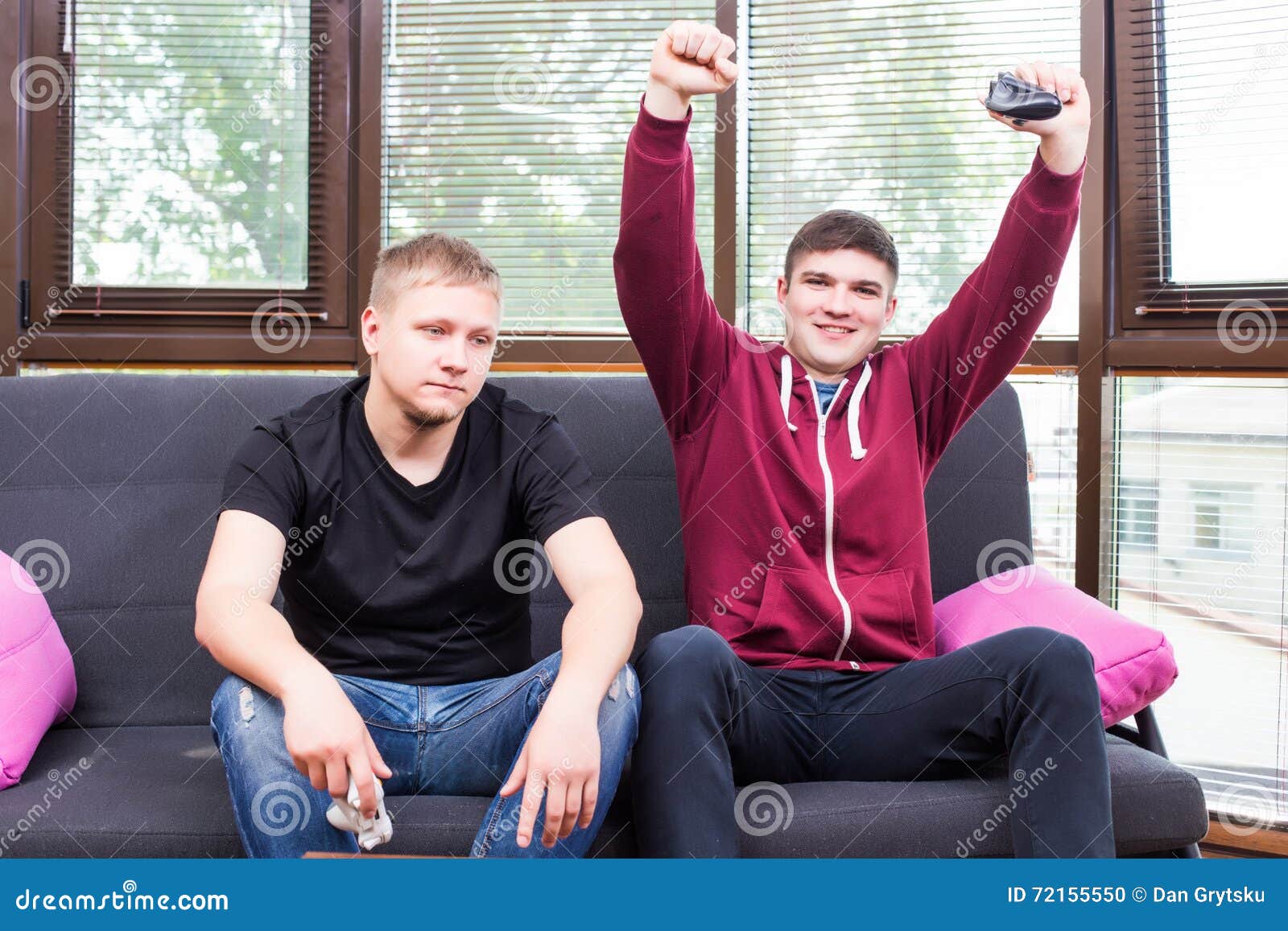 Two Handsome Young Men Playing Video Games while Sitting on Sofa Stock ...