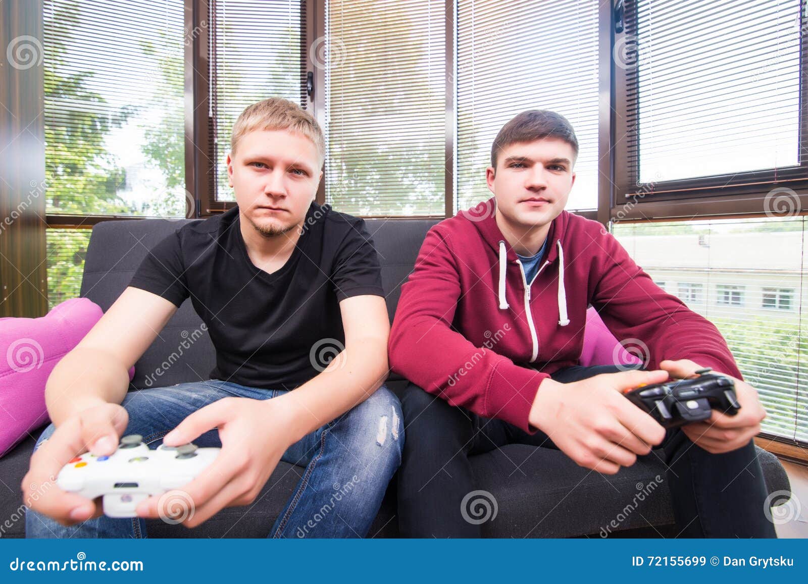 Two Handsome Young Men Playing Video Games while Sitting on Sofa Stock ...