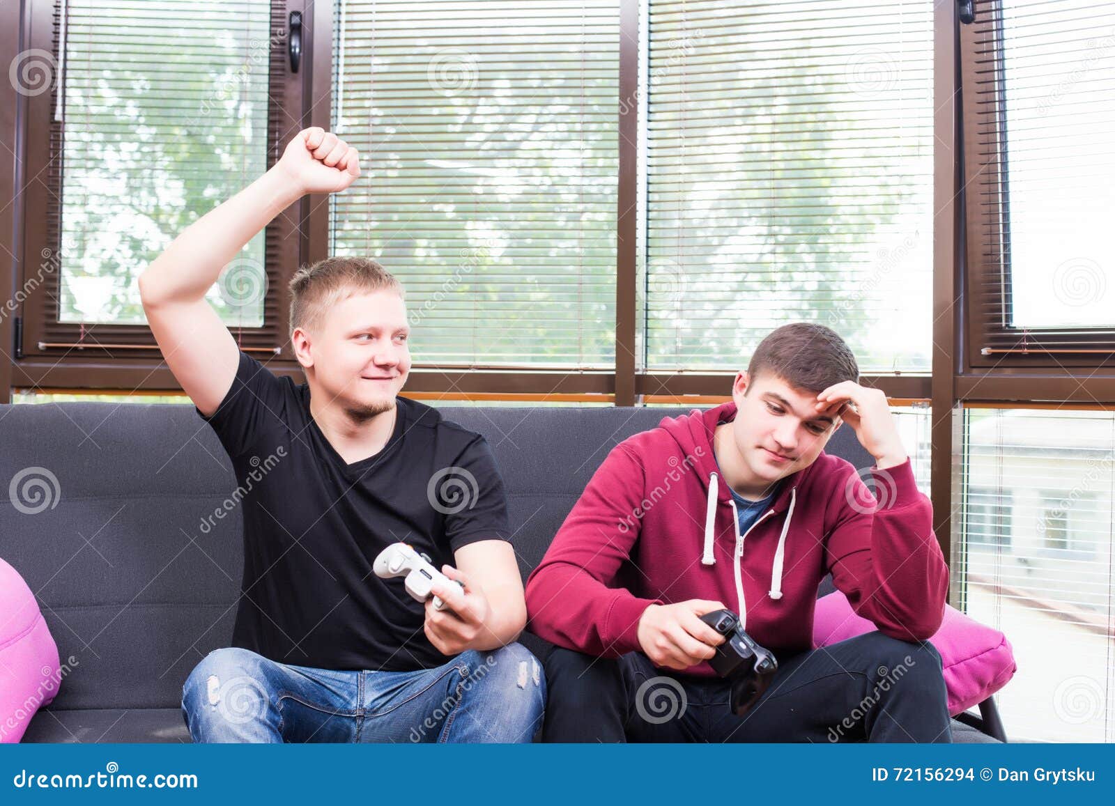 Two Handsome Young Men Playing Video Games while Sitting on Sofa Stock ...