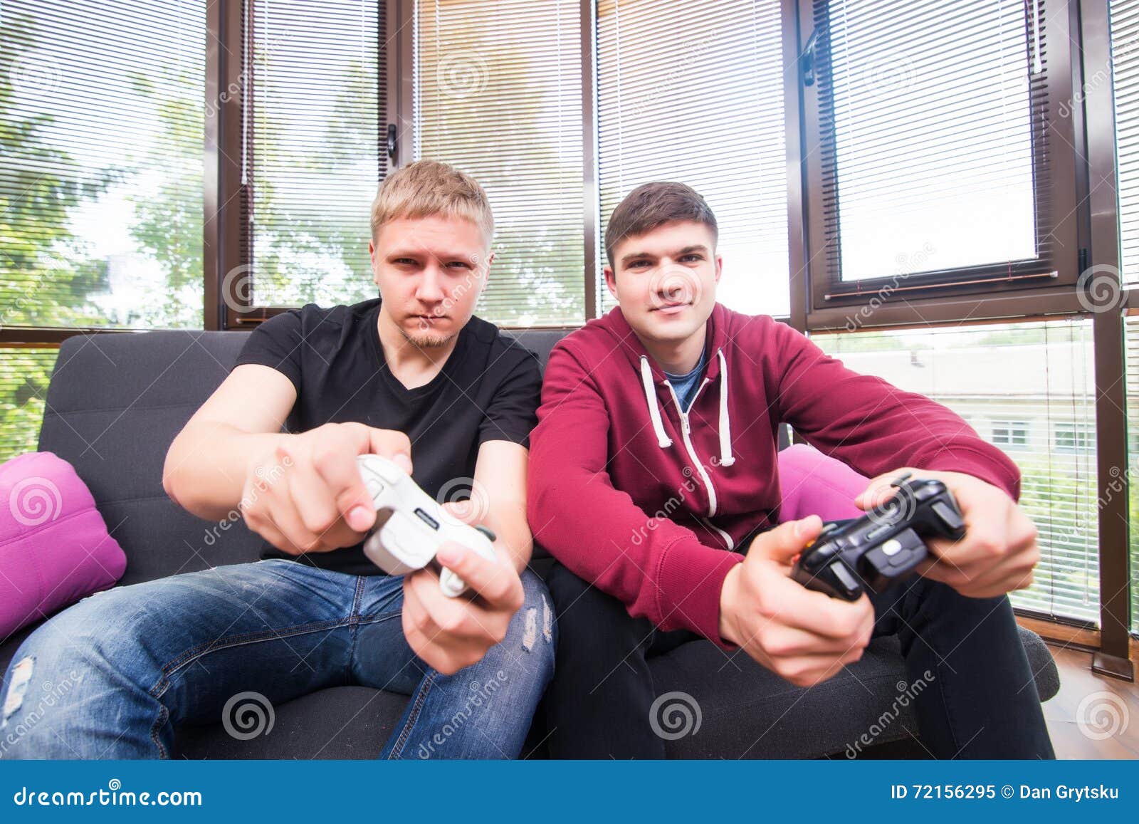 Two Handsome Young Men Playing Video Games while Sitting on Sofa Stock ...